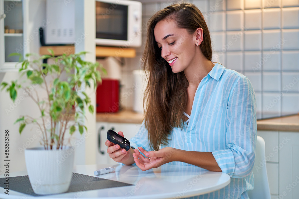 Young woman checks and measures blood glucose level using glucose meter ...