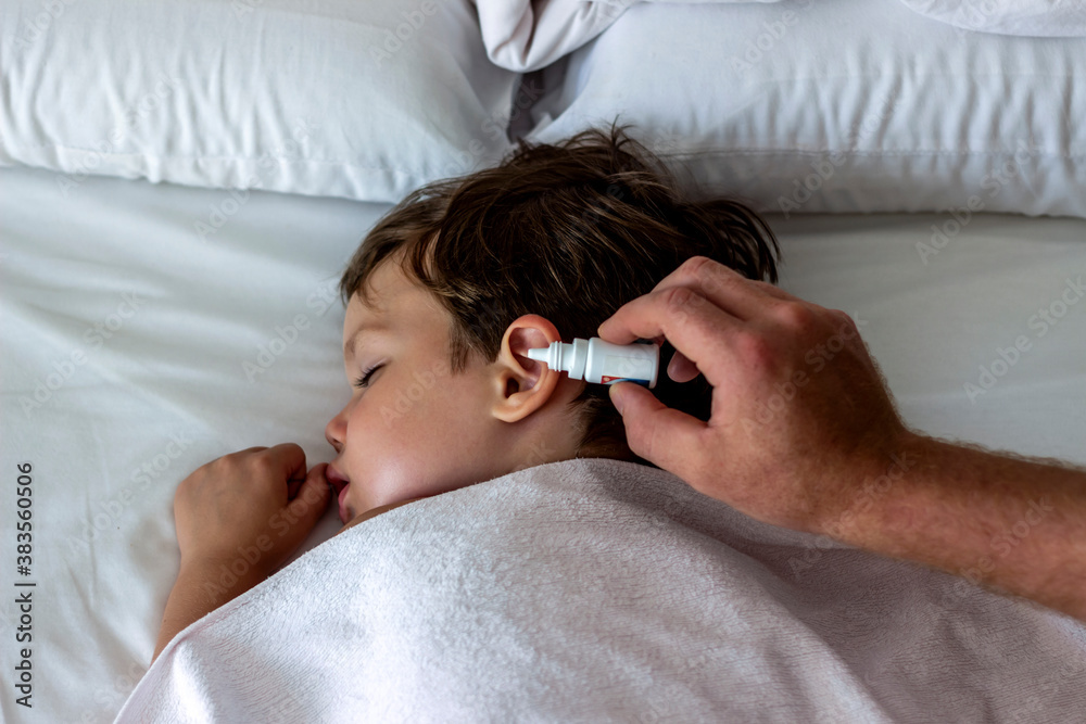 Medical pipette with a drop of medication over the boys ear. Man ...