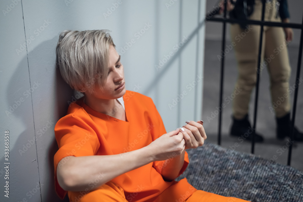 Sad girl criminal thinks about his fate, sitting on a prison bed. Stock ...