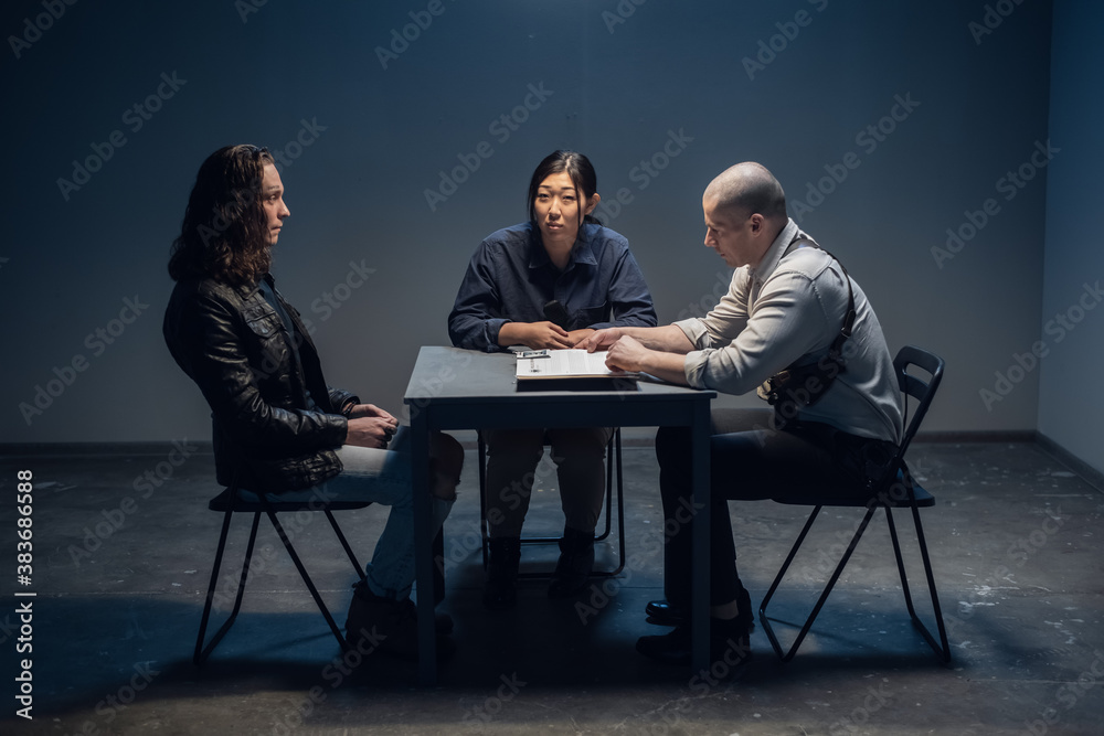 A tough police detective interrogates a crime suspect with a tattooed ...