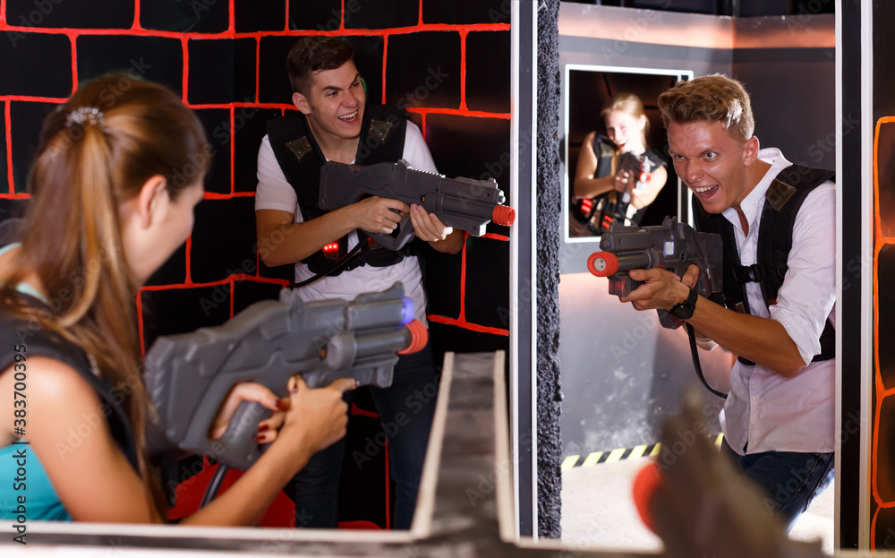 friends with plastic laser pistols in their hands playing laser tag ...