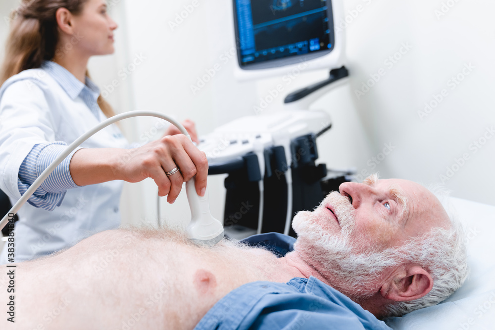 Stockfoto Elderly male patient undergoing examination chest by female ...