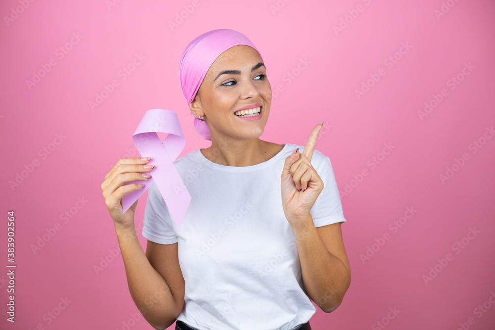 Young beautiful woman wearing pink headscarf holding brest cancer ...