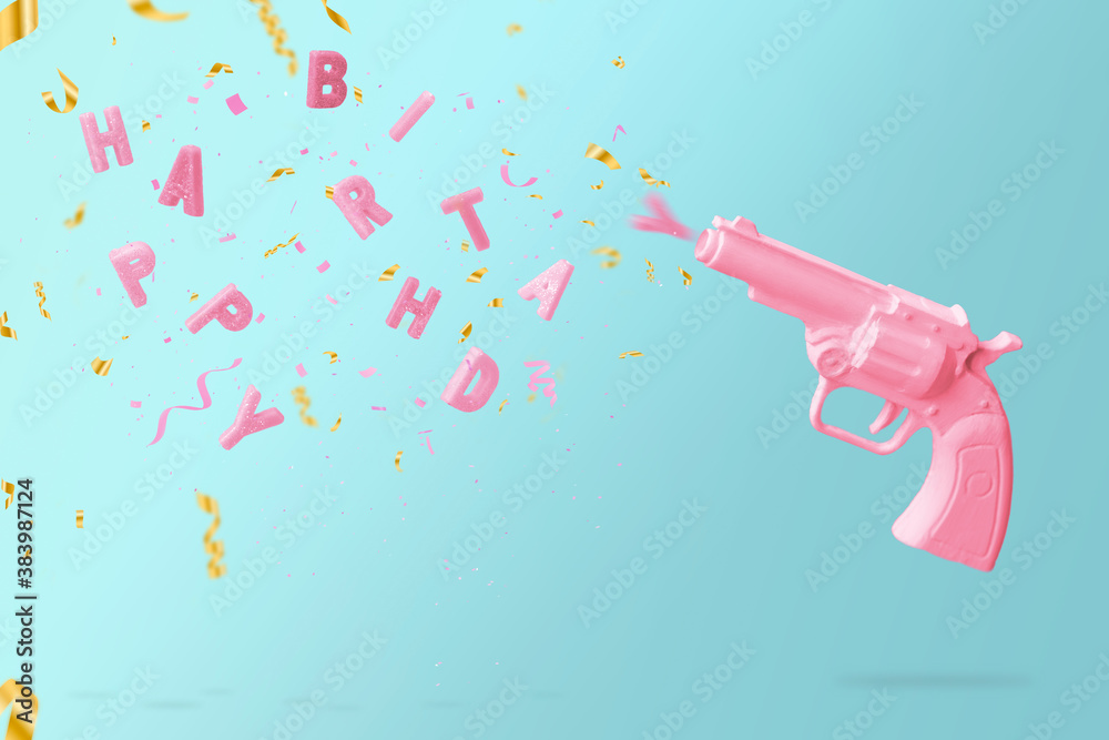 Pink gun shooting birthday candles and colorful confetti, against blue ...