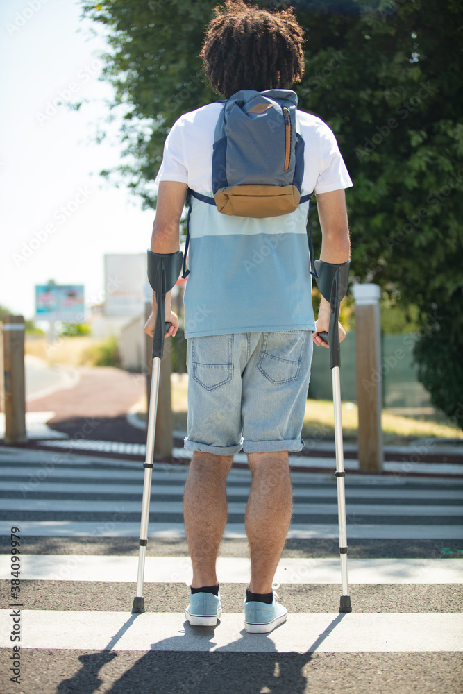 disabled person on crutches crosses the carriageway at a crosswalk ...