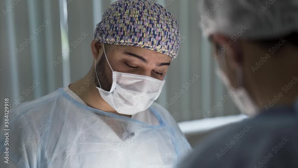 Close up of two male surgeons looking down at work. Action. Men doctors ...