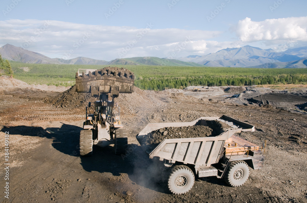 Loading of mountain soil into the body of a mining dump truck using a ...