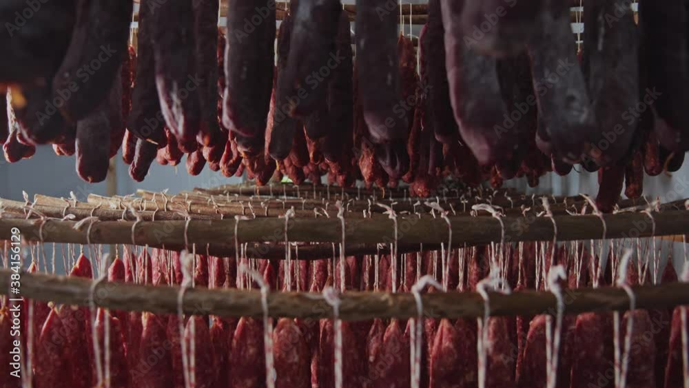 Closeup of spicy smoked sausage and salami sticks hanging on ropes at ...