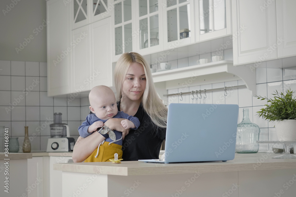 Mother multi-tasking, holding baby infant and using computer laptop at ...