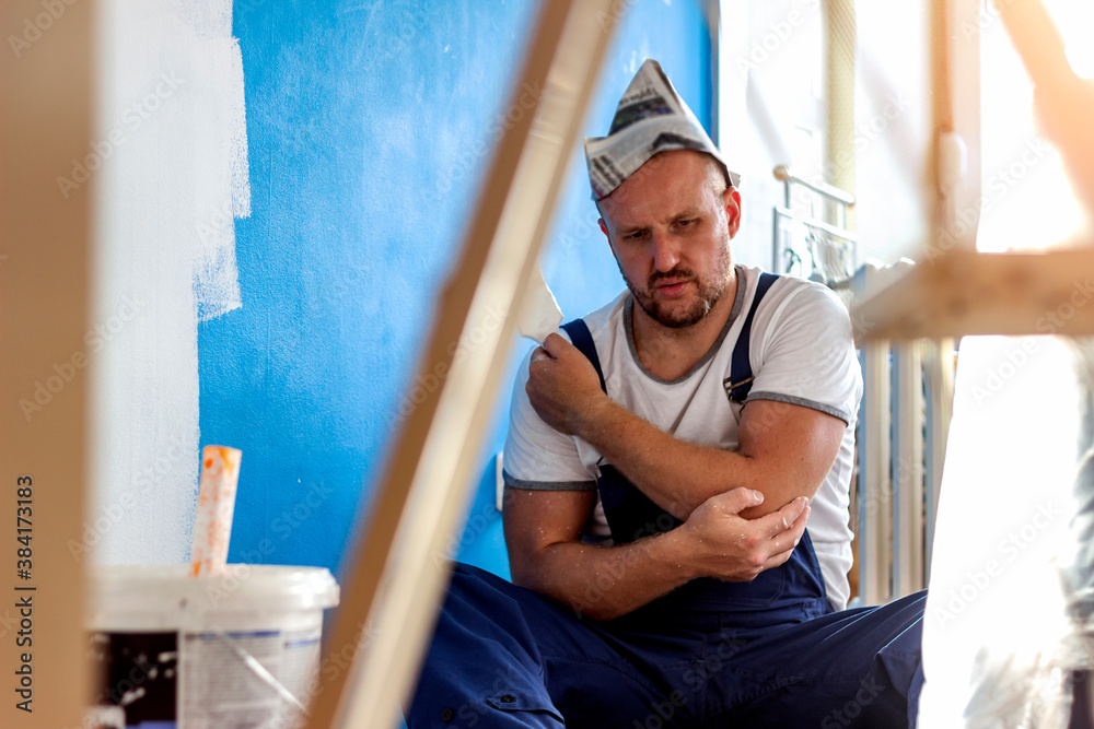 Shot of exhausted painter suffering from pain in his shoulder after ...