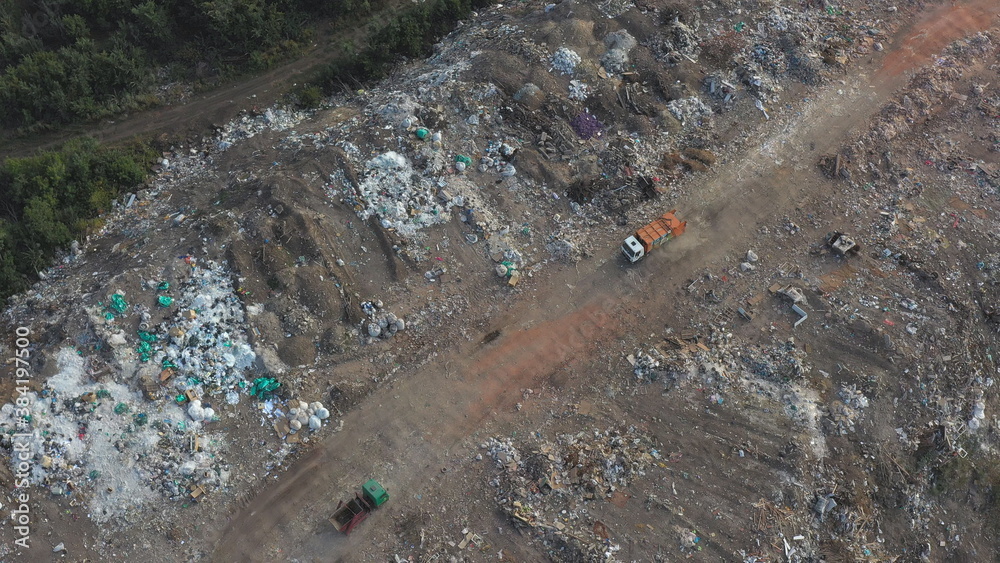 Flying over industrial trucks dumping trash at open places at nature ...