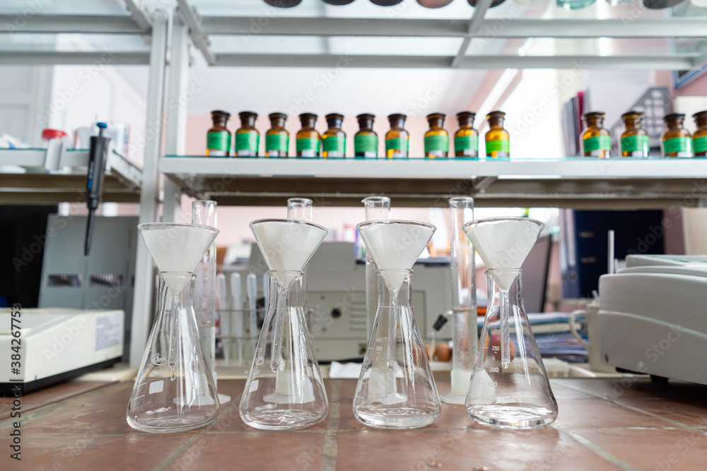 Row of glass measurement flasks with paper filters inside on a ceramic ...