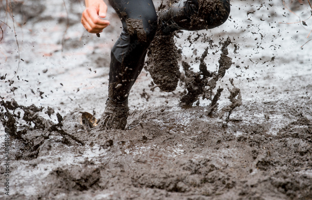 Mud race runner, man running in mud. Runners during extreme obstacle ...