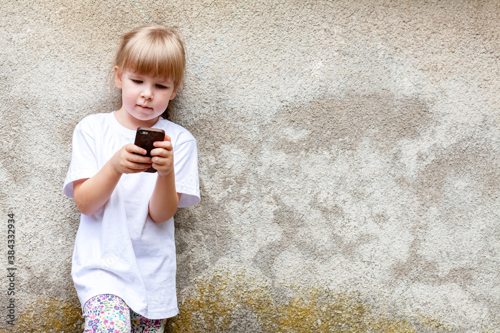 Little girl, child using a modern smartphone standing outdoors. Kid ...