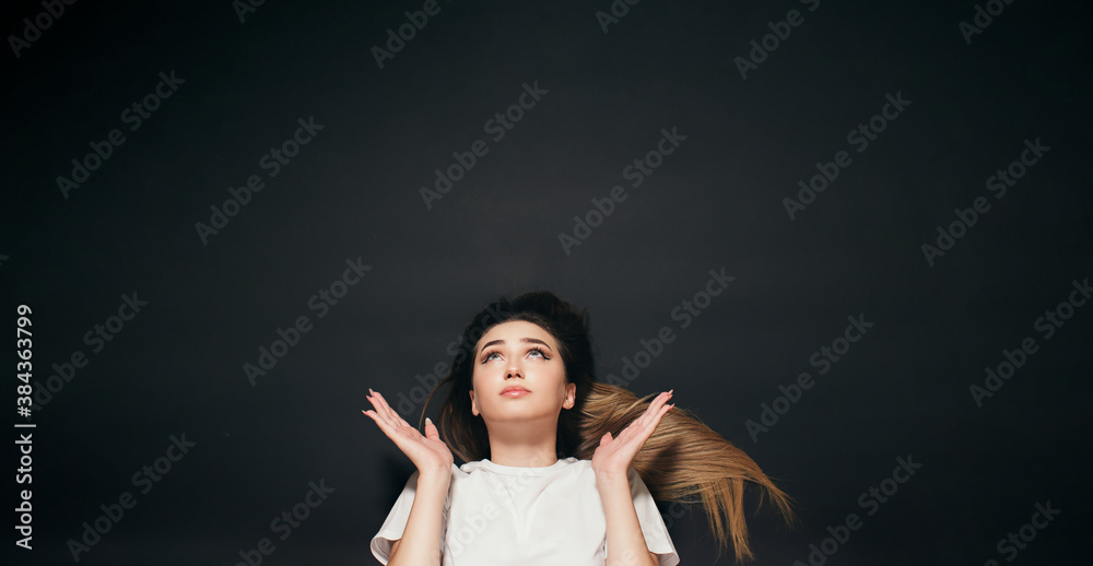 young woman with long hair looking pleadingly upward, spread arms to ...