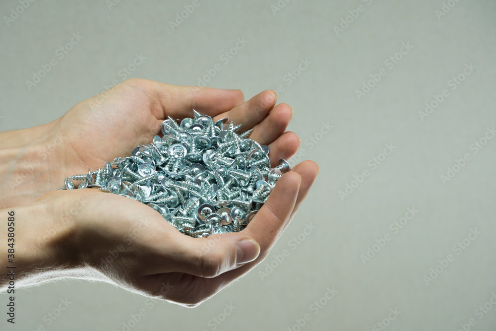 Fotka „Bolts in a man's hands. Screws and cogs. Tools for fixing and ...
