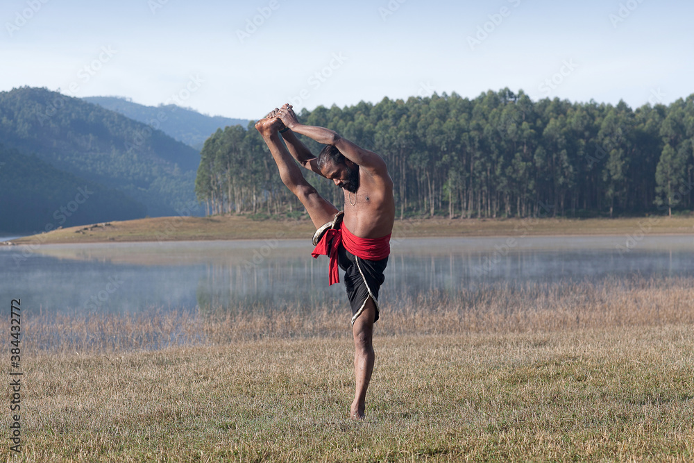 Indian Kalaripayattu warrior doing yoga exercise on green grass in ...