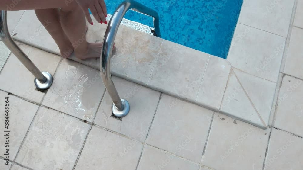 Happy young woman wearing black swimsuit on ladder getting in the ...