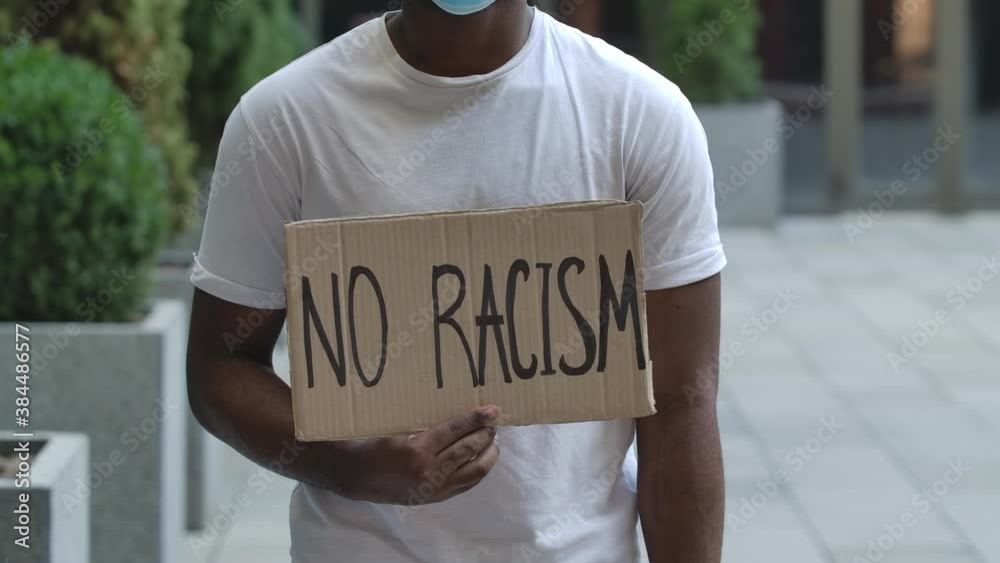 An African American stands in the middle of the street holding a ...