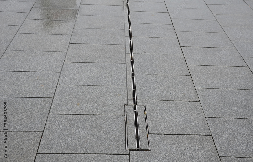 large-format paving made of gray granite. the water is drained in the ...