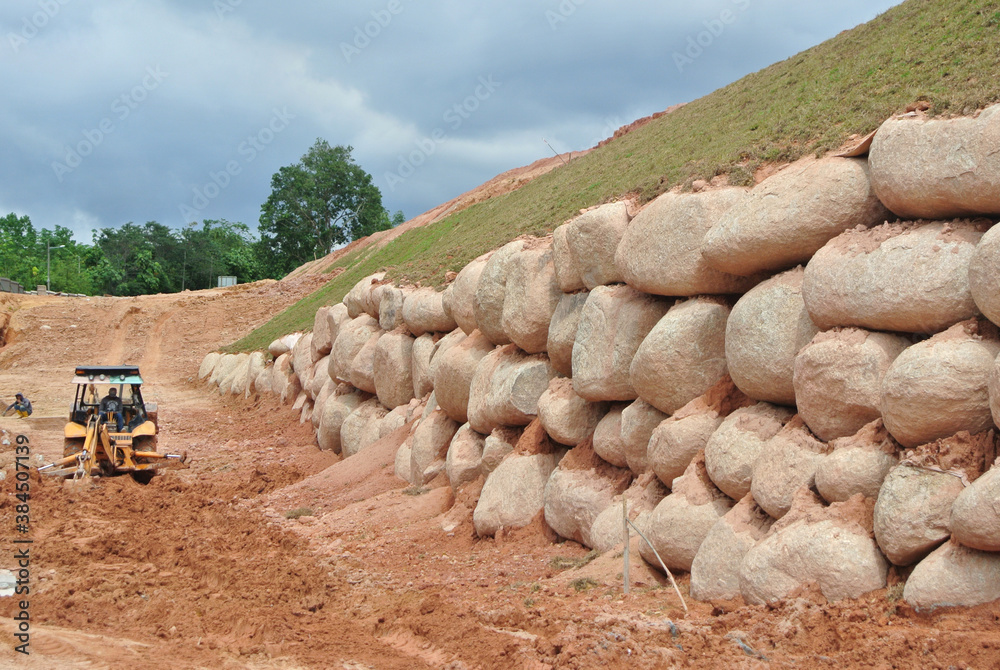 Stone boulders are stacked on the ground and used as retaining walls ...