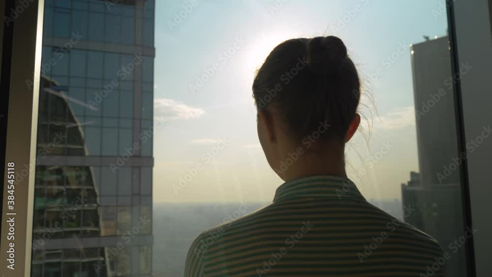 Back view of woman silhouette looking at cityscape through window of ...