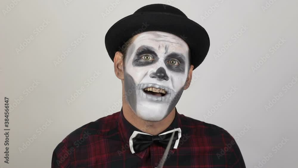 A horrible man in clown makeup threatens his victim with a sharp knife ...