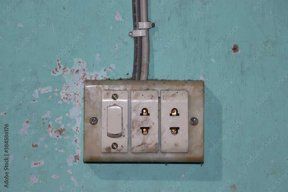 An old electrical switchboard with sockets attached to the painted wall ...