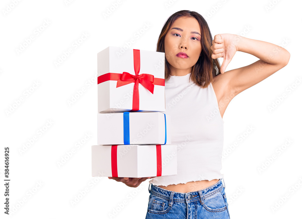 Young beautiful chinese girl holding gift with angry face, negative ...