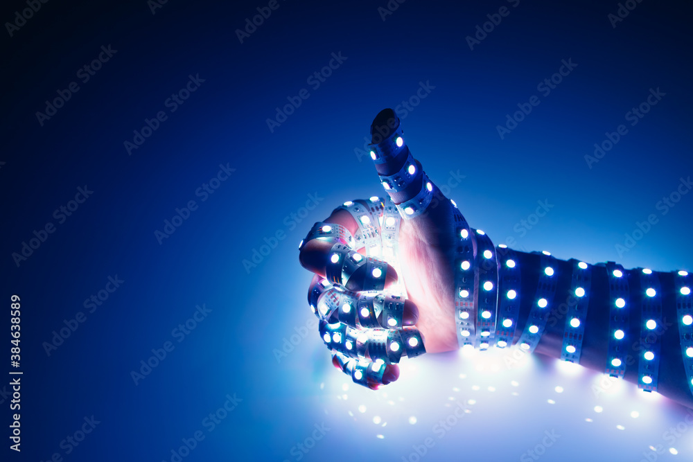 thumbs up hand covered with blue led lights, illuminated background ...