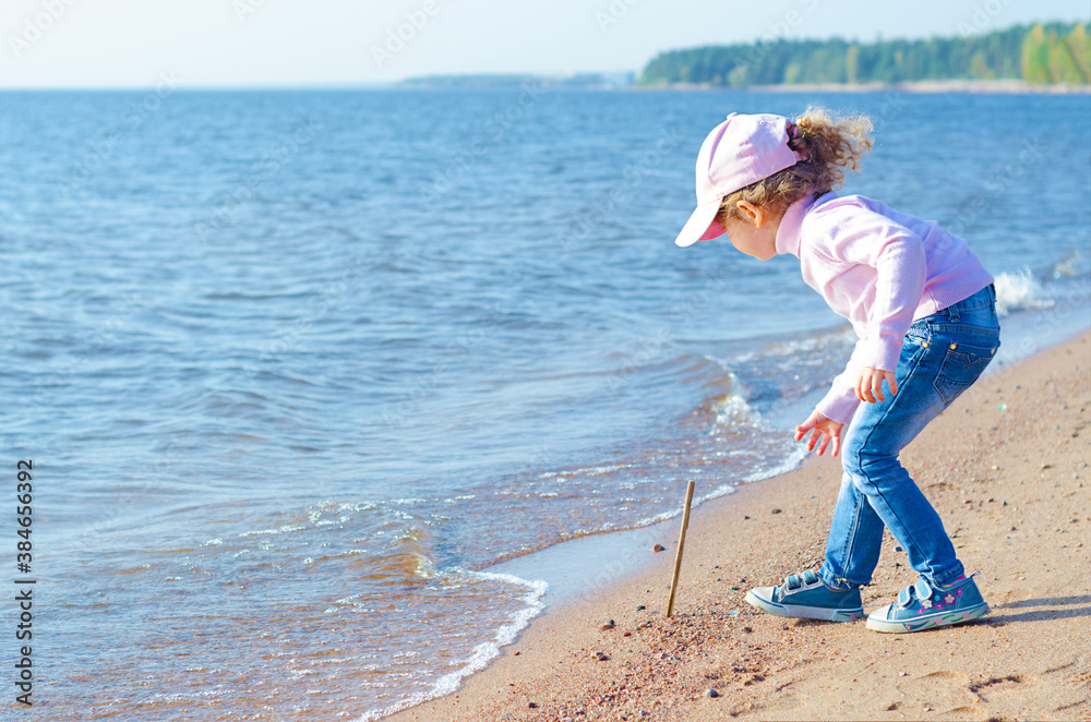 little girl playing on the seashore in the sand. Volunteer child ...