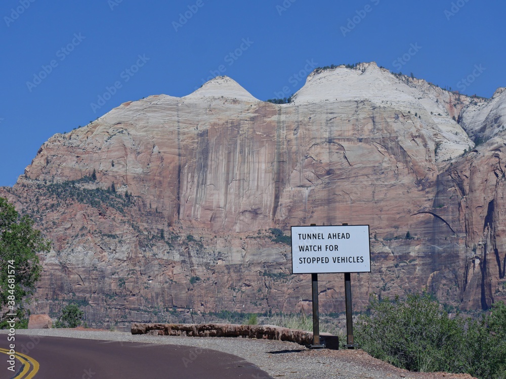 Steep limestone cliff with roadside sign for the Zion-Mt. Carmel tunnel ...