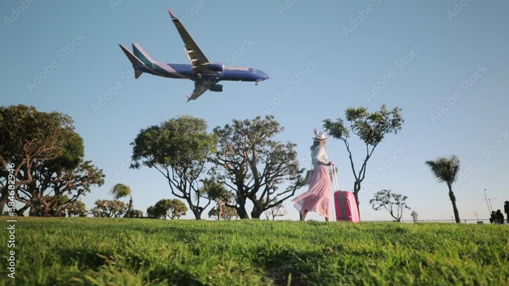 Slow motion arriving airliner at the airport. Stylish traveler woman is ...