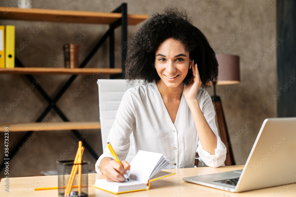 A beautiful black woman in smart casual wear is using laptop computer ...