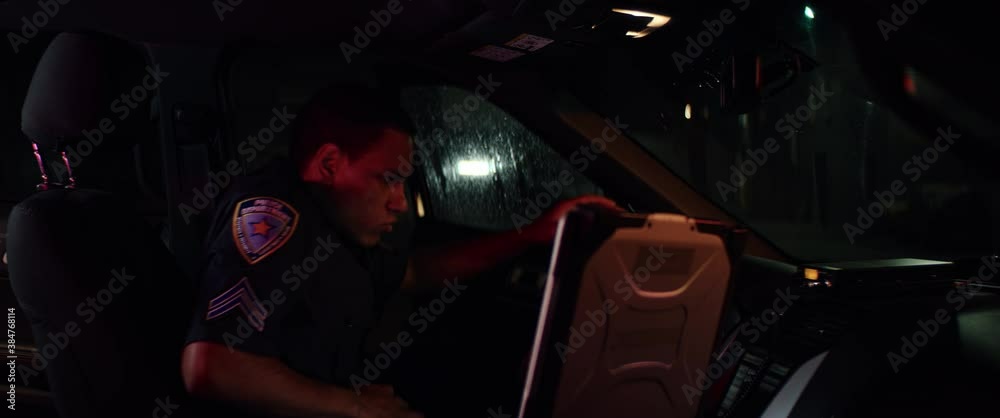 African-American officer getting into the police car on a rainy night ...