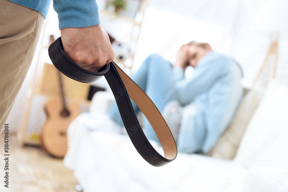 Father comes to his son with belt ho hit him. Stock-Foto | Adobe Stock