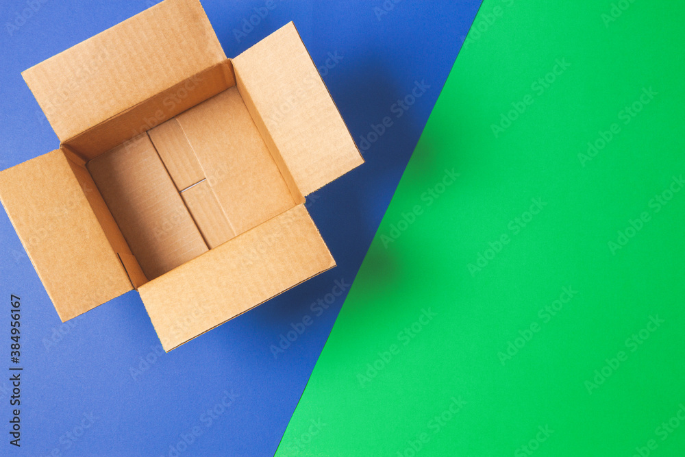 One empty open cardboard box on geometric green, light blue background ...