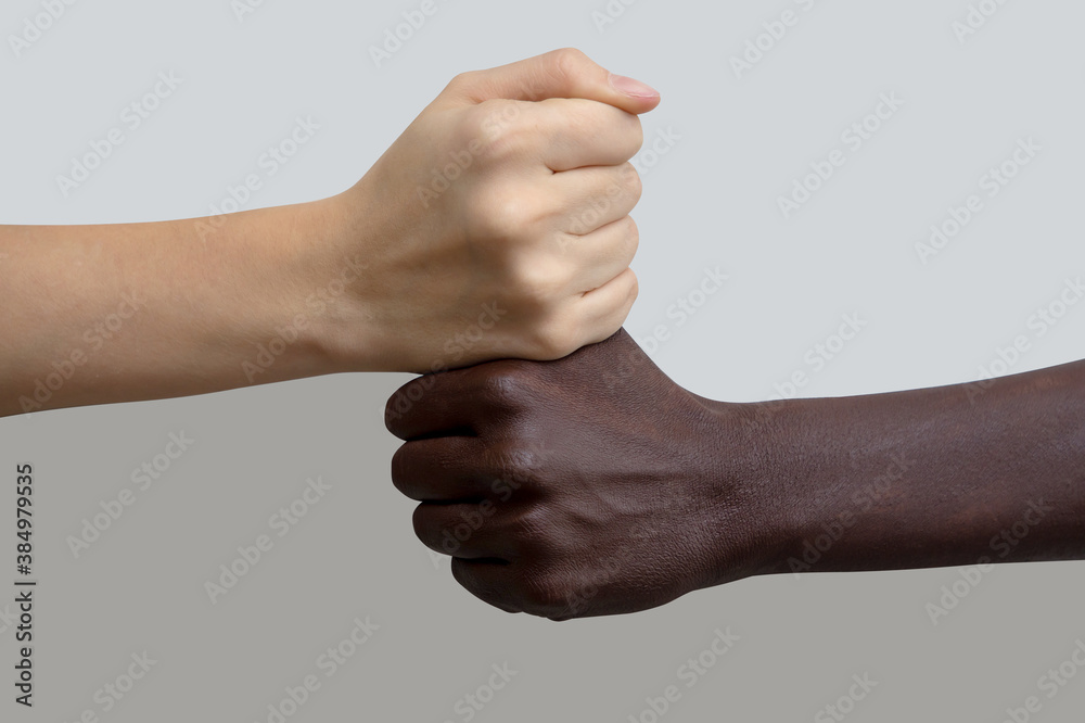 A white hand in the shape of a fist, lying on top of a dark-skinned ...