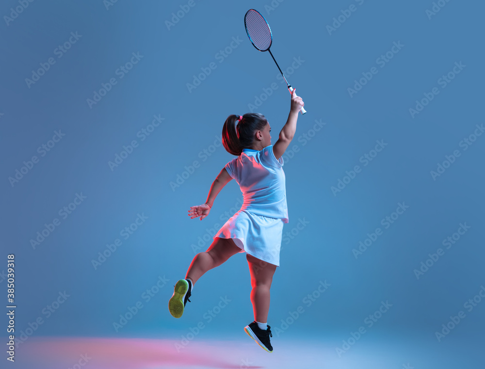 Strong. Beautiful dwarf woman practicing in badminton isolated on blue background in neon light ...