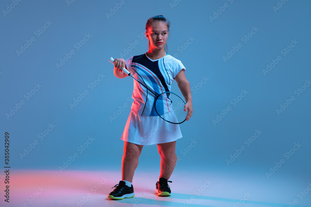 Dynamic. Beautiful dwarf woman practicing in badminton isolated on blue ...