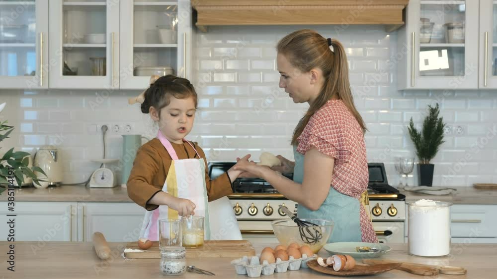 Mom wipes the baby's hands and dusts off the flour while cooking in the ...