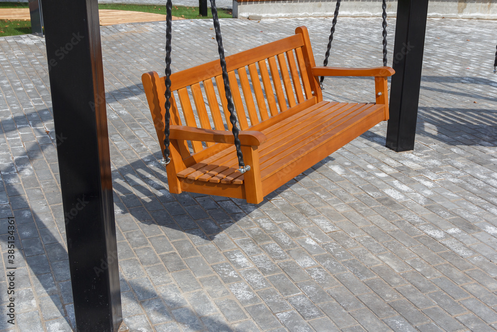 New swing bench in the park. Swing in the form of a wooden park bench ...