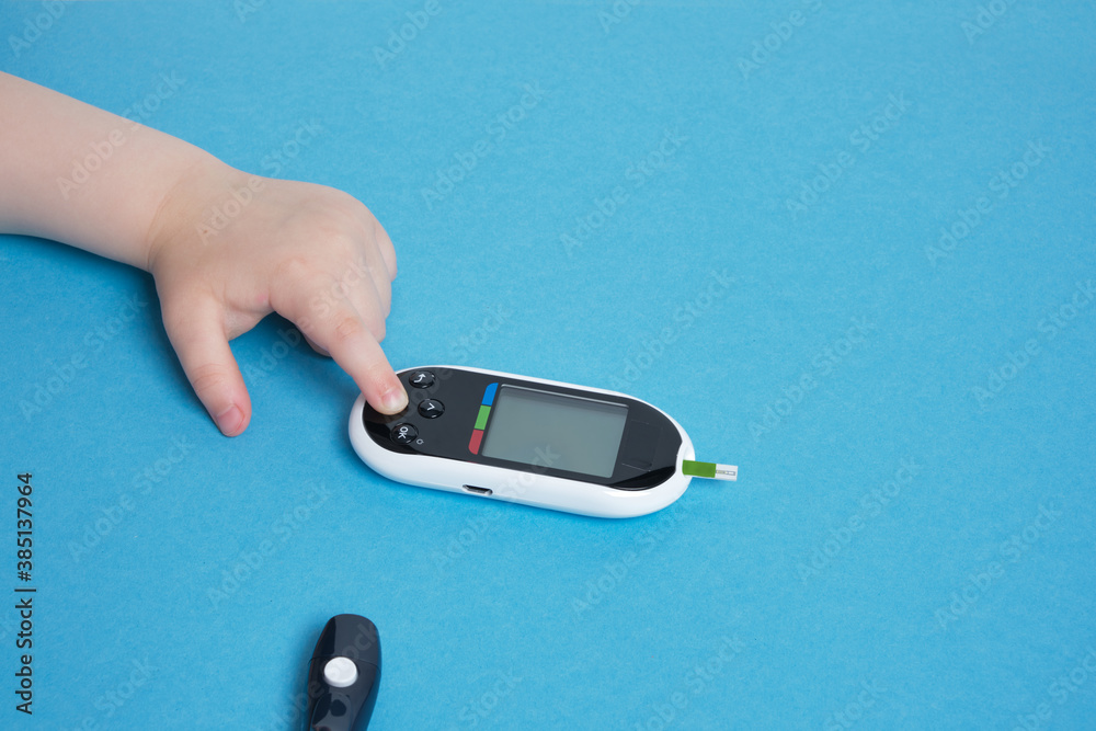 small child presses the button glucose meter, blood glucose meter ...