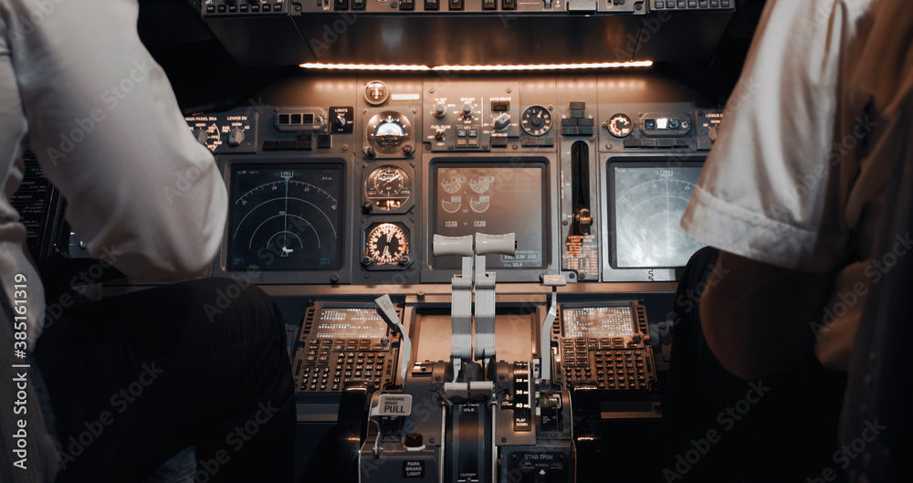 Pilots sitting at control panel in flight deck Stock Photo | Adobe Stock