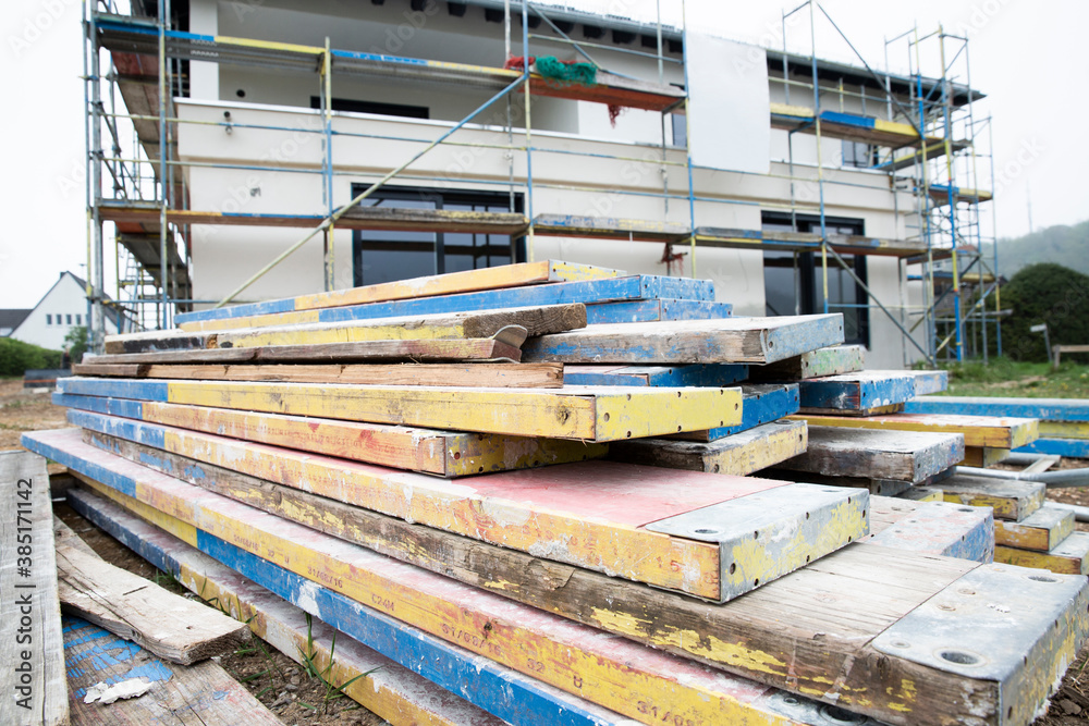 Planks stacked against house at construction site Stock Photo | Adobe Stock