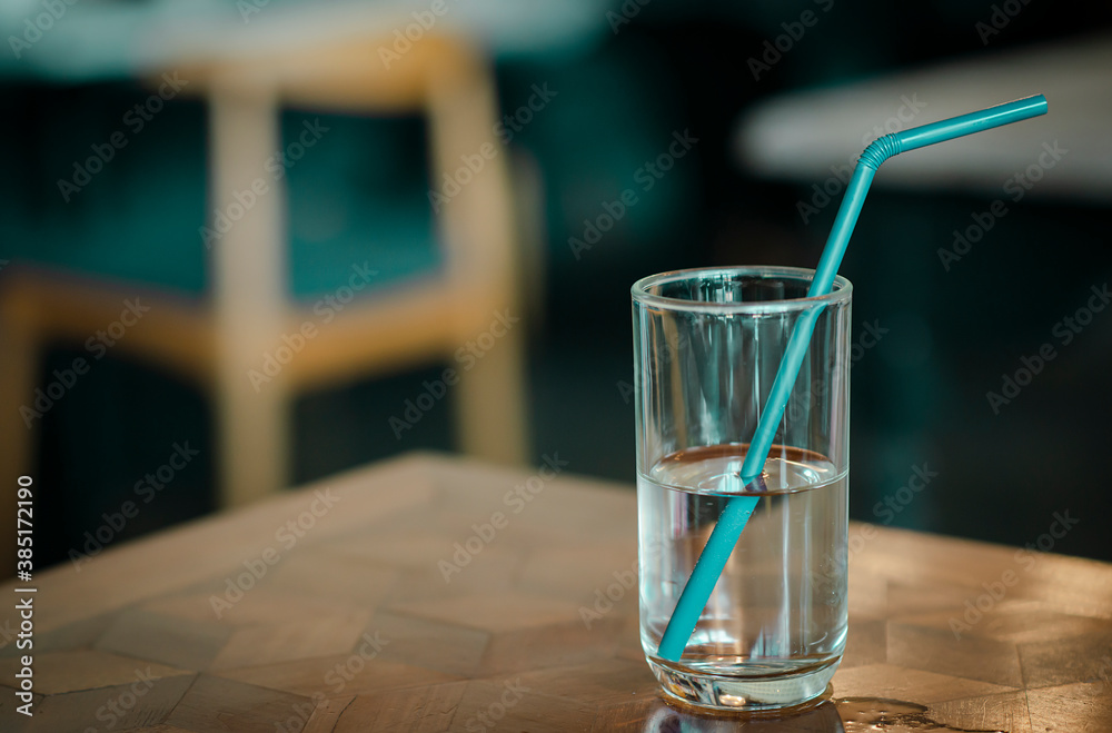 A glass of water with Green drinking straw on wood table background in ...