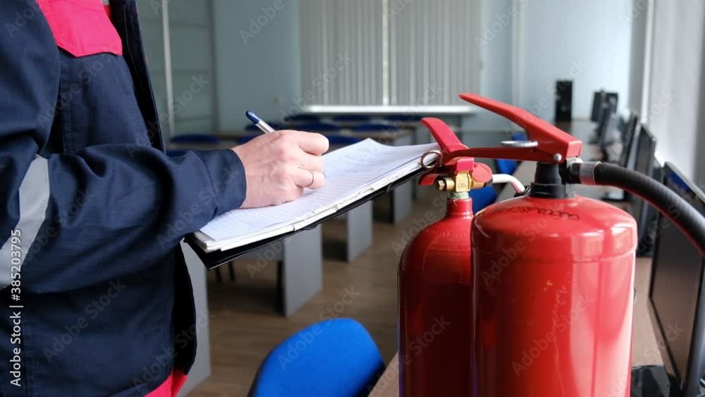 Engineer Professional are Checking A Fire Extinguisher and writes data ...
