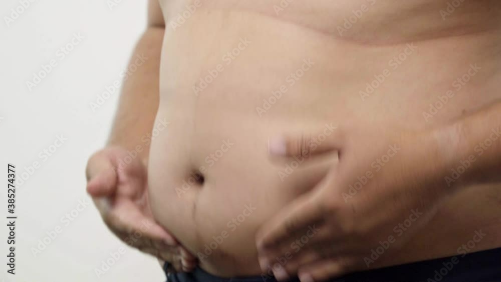 Close up of a big male stomach. The fat man checks his waist, he is ...