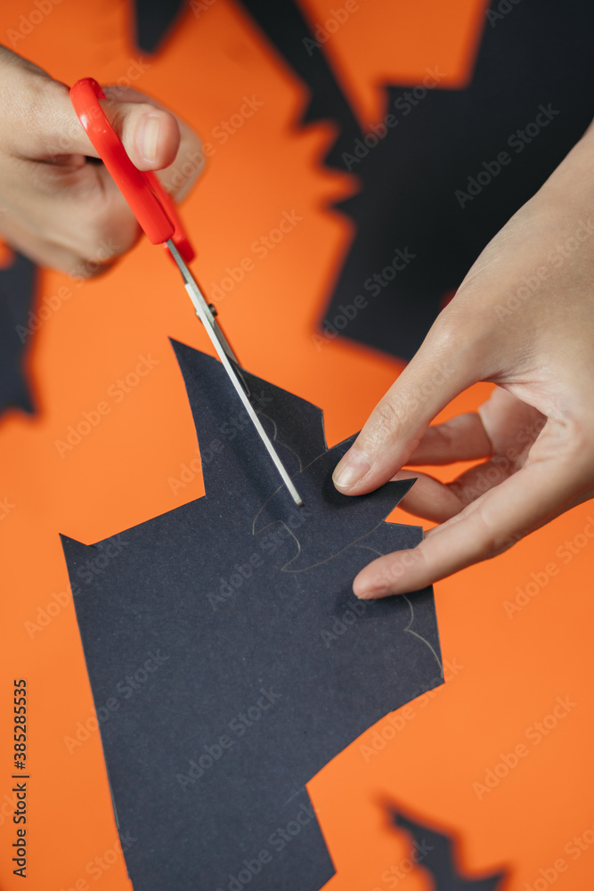 Overhead closeup shot of a woman cutting out bat shapes from black ...