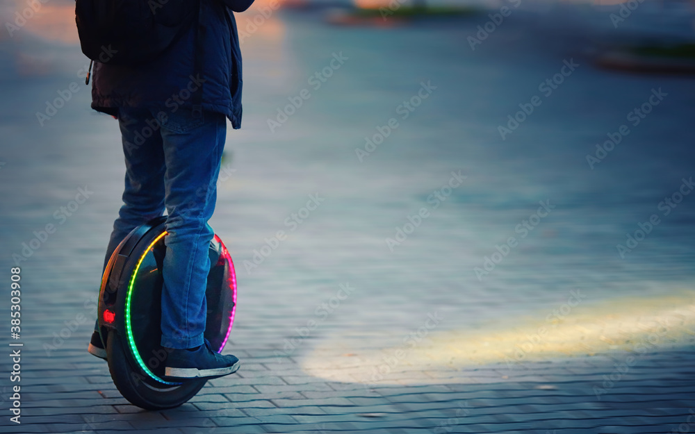 .Man riding fast on electric unicycle on city street at night with ...